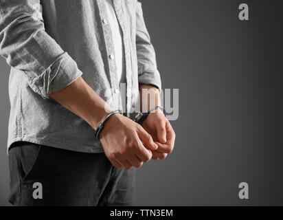 Man in handcuffs on grey background Stock Photo - Alamy