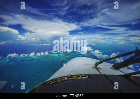 Cropped image of airplane flying against blue sky over scenic view of ...