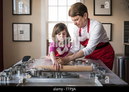 Grandmother and her granddaughter making cookies together at table in ...