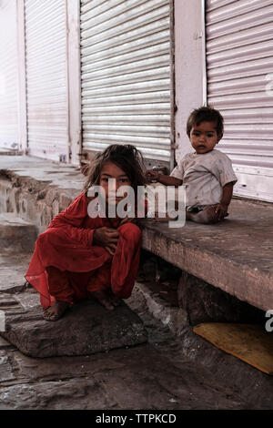 Sad girl crouching in front of wooden wall hiding her face Stock Photo ...