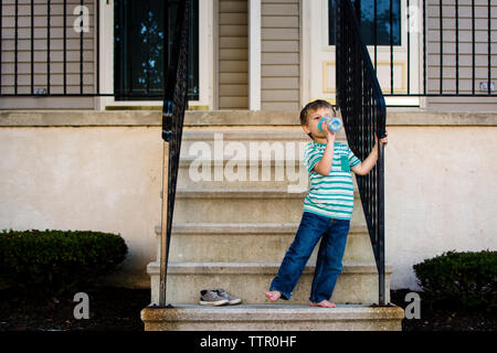 Boy drinking water while standing on grassy field against sky in park ...