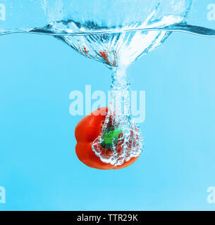 Pepper falling into water on color background Stock Photo - Alamy
