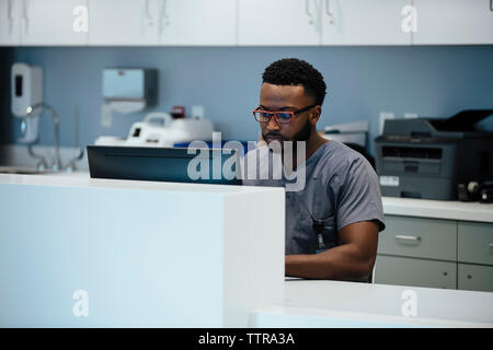 Doctor using desktop computer at reception while hospital staff working ...