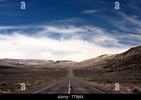 Empty road amidst field against sky Stock Photo - Alamy