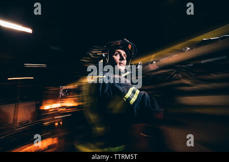 Firefighter riding on outside of fire truck at night Stock Photo - Alamy