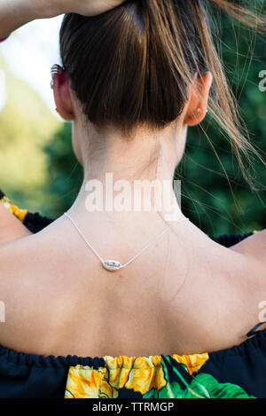 Rear view of a young woman tying her long hair on white background ...