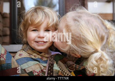 Two cute blond sisters kissing outdoors Stock Photo - Alamy