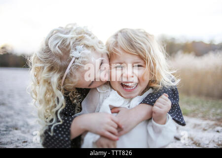 Two cute blond sisters kissing outdoors Stock Photo - Alamy