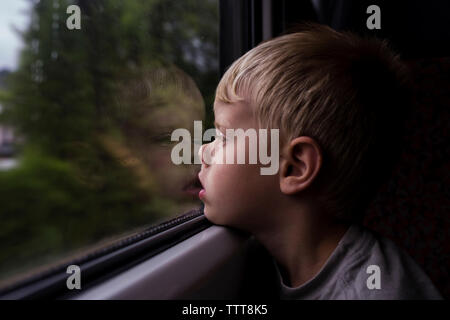 Thoughtful boy looking through train window Stock Photo - Alamy