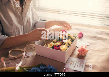 Midsection of young female owner with fabric on wrapping paper at store ...