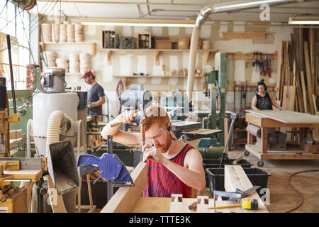 Male and female carpenters working at workbench in industry Stock Photo ...
