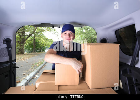 Young male deliverer loading boxes into car Stock Photo - Alamy
