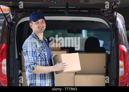 Young male deliverer loading boxes into car Stock Photo - Alamy