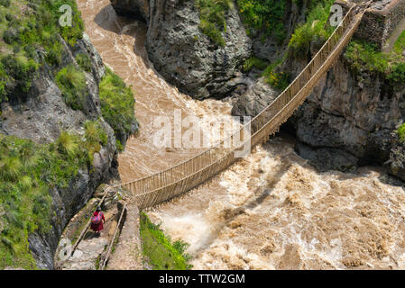 Quechua woman crossing Queshuachaca (Q'eswachaka) rope bridge, one of ...