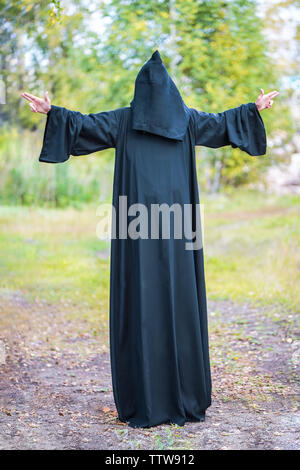 Medieval executioner in a cloak with a hood and a chopping block with ...