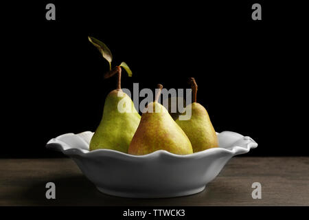 Pears in a plate on a black background Stock Photo - Alamy