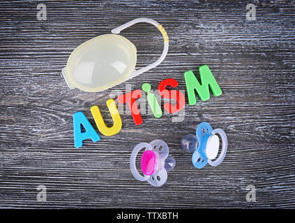 Word AUTISM with pacifiers on wooden background Stock Photo - Alamy