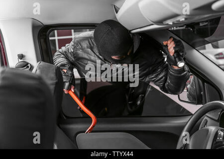 Male thief getting into car through window Stock Photo - Alamy