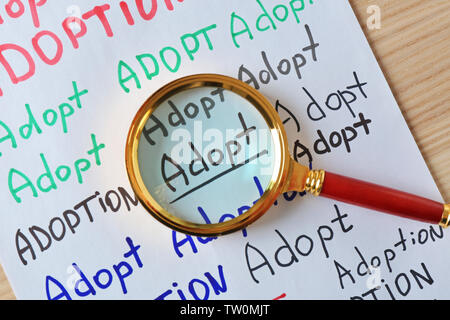 Magnifier and paper with words "Adoption", closeup Stock Photo - Alamy