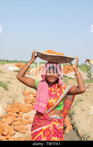 Labor carrying brick on head at construction site Stock Photo - Alamy