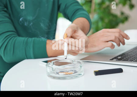 Male hand ashing his cigarette into ashtray, closeup Stock Photo - Alamy