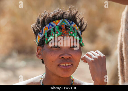 Bushmen woman of the San people making jewelry of ostrich egg shell ...
