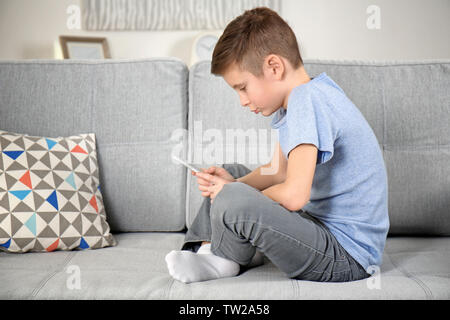 Boy with incorrect posture and phone sitting on chair against light ...