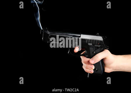 Male hand holding smoking gun on black background Stock Photo - Alamy