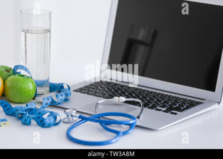 Composition with measuring tape, stethoscope and computer on table in ...