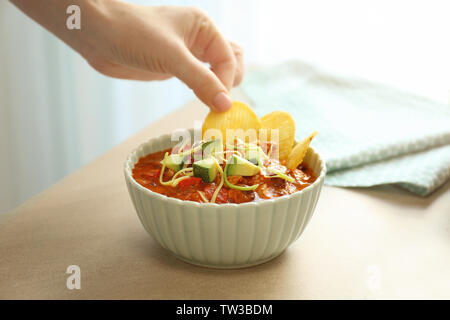 Female hand putting chips into bowl with chili turkey, closeup Stock ...