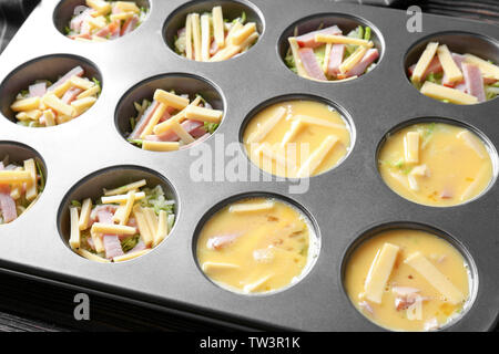 Baking mold with tasty eggs and ham on table Stock Photo - Alamy