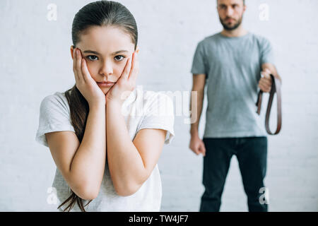 partial view of father with belt and upset kids sitting on floor Stock ...