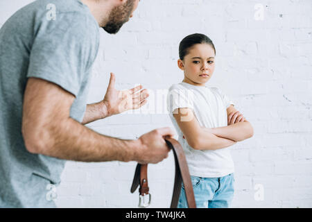 partial view of father with belt and upset kids sitting on floor Stock ...