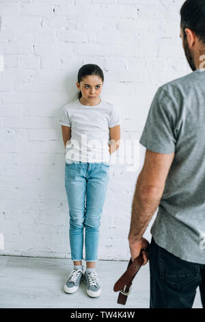 cropped view of father holding belt and standing near daughter Stock ...