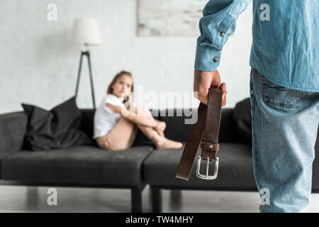 cropped view of father holding belt and standing near daughter Stock ...