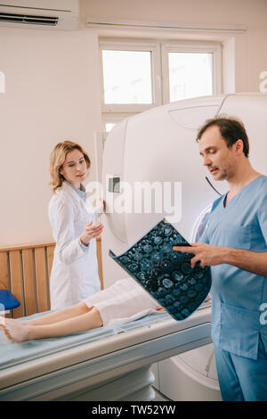 CT scanning. Radiologist examining CT (computed tomography) scans of ...