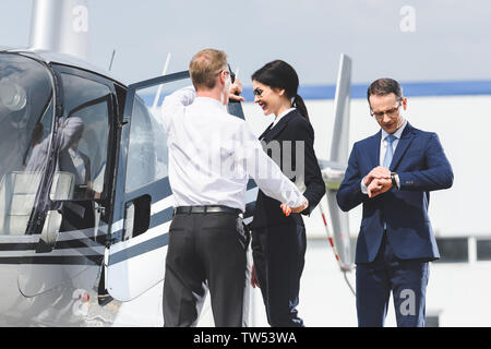businesspeople in formal wear near helicopter and Pilot Stock Photo - Alamy