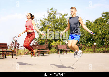 Young man and woman with jumping ropes in park Stock Photo - Alamy