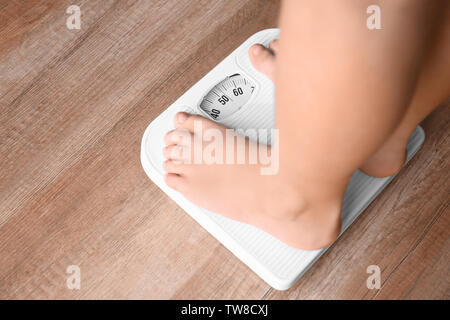 Overweight boy using scales at home Stock Photo - Alamy