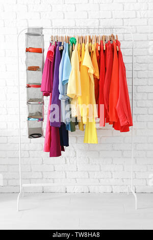 Rack with rainbow clothes near brick wall Stock Photo - Alamy