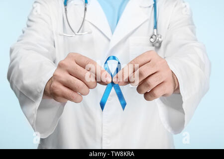 Doctor holding blue ribbon on white background. Prostate cancer concept ...