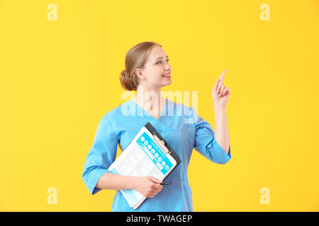 Young medical assistant with documents pointing at something on color ...