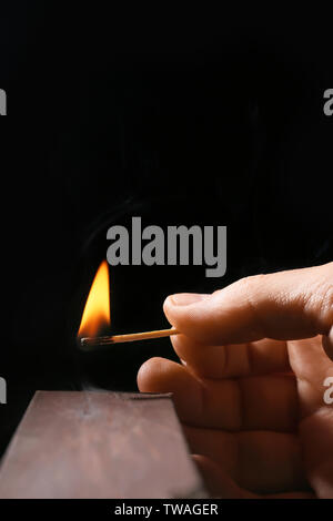Man striking match on dark background Stock Photo - Alamy