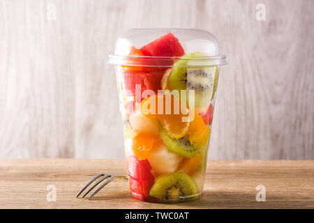 Delicious fruit cocktail in a plastic cup, on a black background ...