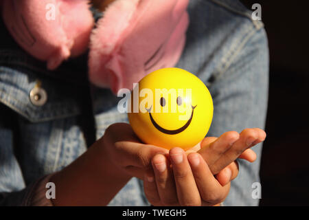 Girl showing a ball with smiley face Stock Photo - Alamy