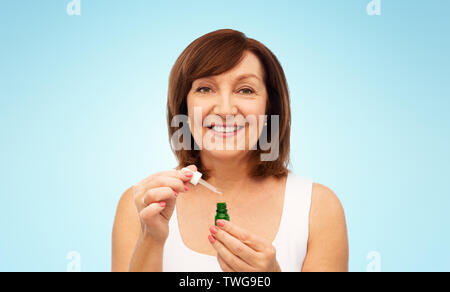 beautiful woman holding bottle with serum for skin care on beige ...