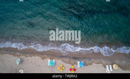 View of sun beds and umbrellas on sandy beach on turquoise water ...