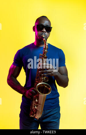 african american man in yellow shirt holding clock isolated on blue ...