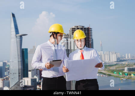 View of a Engineer and worker watching blueprint on construction site ...