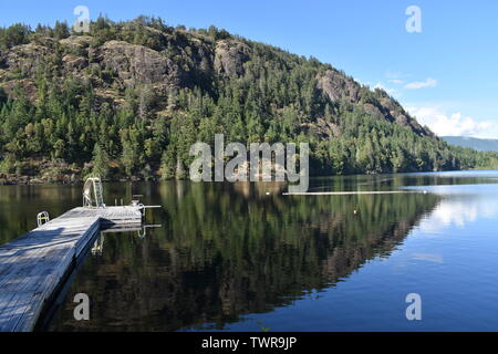 Dock at the beach on a calm mountain lake Stock Photo - Alamy